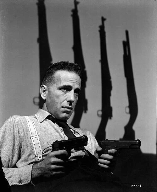 HUMPHREY BOGART POINTING two guns as he appears in the movie 'High- Old ...