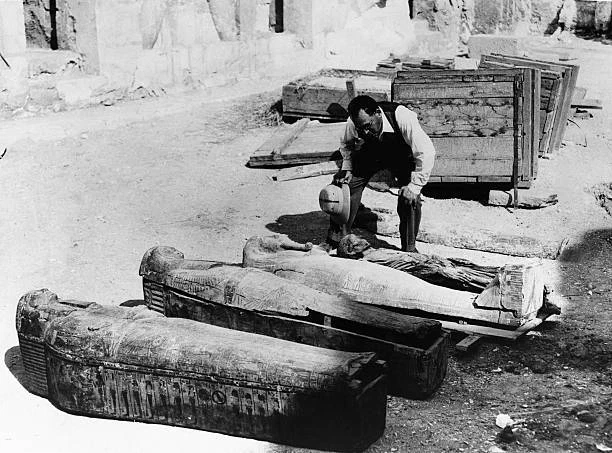 ARCHAEOLOGIST DR ZACARIA examines mummies found in an uncovered tomb ...