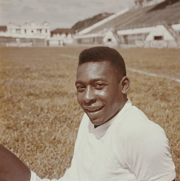 BRAZILIAN FOOTBALLER PELE posed sitting on a football pitch 1960s Old ...