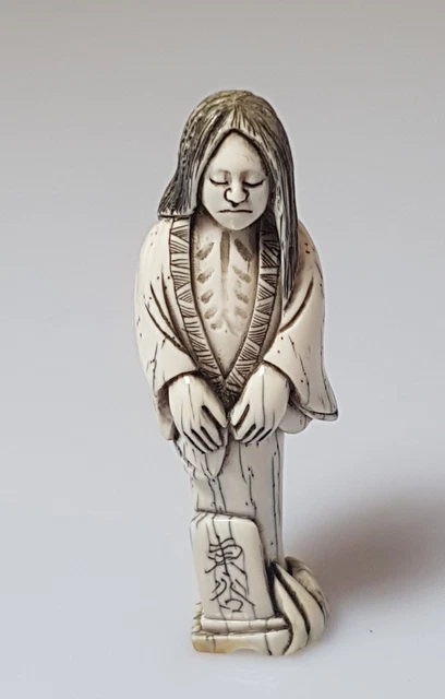 A MEIJI PERIOD Netsuke of a female Ghost stood by a Tombstone. Signed ...