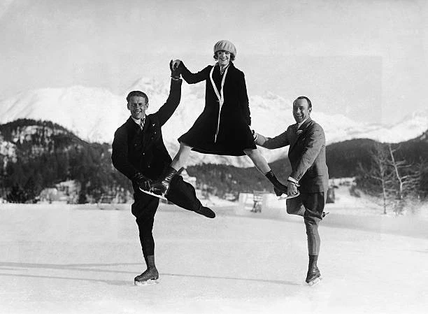 THREE ICE SKATERS Are Shown Doing An Acrobatic Stunt. The Two Men Ar ...